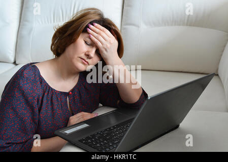 Woman with headache uses a computer at home Stock Photo - Alamy
