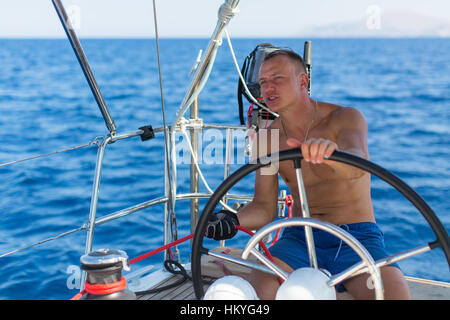 Man skipper at the helm controls of a sailing yacht during sea boats ...