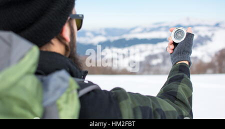 Hipster man using a compass on a snowy mountain Stock Photo - Alamy
