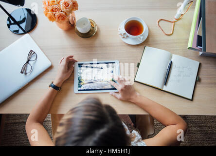 Overhead view of businesswoman using tablet computer while sitting at ...