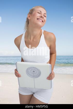 Young woman holding a scale over isolated pink background with weighing ...
