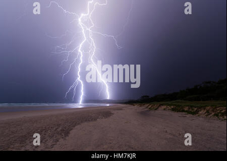 Lightning strikes a sand dune and the ocean during an electrical storm ...