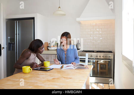 Two friends researching recipes at the kitchen table Stock Photo - Alamy