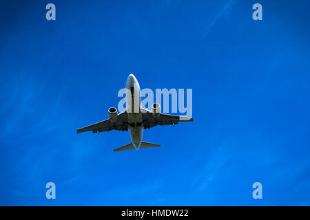 Jet airplane flying overhead close-up on a blue sky background Stock ...