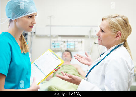 Doctors talking next to sleeping patient Stock Photo - Alamy