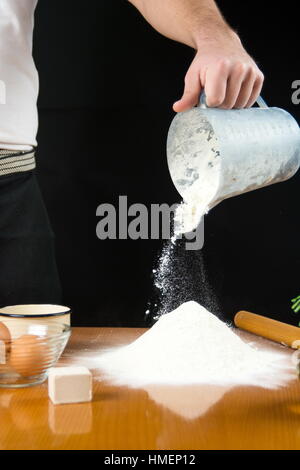 Man pouring flour from the measure bowl on the table Stock Photo ...