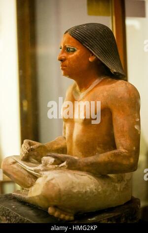painted limestone statue of an Egyptian scribe seated cross-legged ...