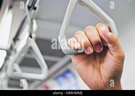 People holding handles on train Stock Photo: 62499160 - Alamy