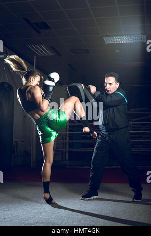 Girl doing knee kick exercise during kickboxing training with personal ...