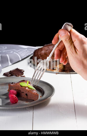 Man hand try a piece of cake chocolate brownie with raspberries and ...