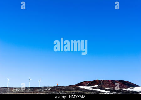 Wind turbines on a barren volcanic hill shrouded in cloud in Antarctica ...