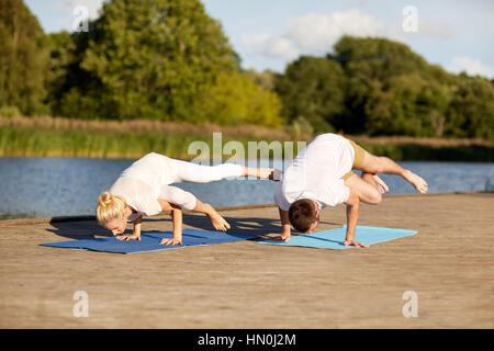 couple making yoga side crane pose over beach Stock Photo - Alamy