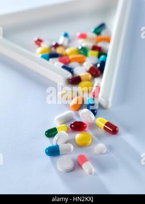 Pills pouring out of measuring triangle Stock Photo - Alamy