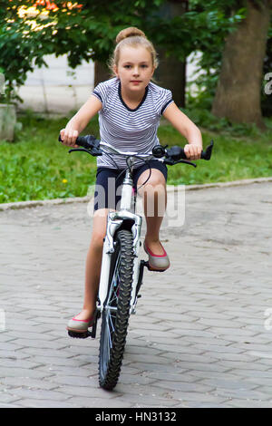 Photo of cute girl driving bicycle in summer Stock Photo - Alamy