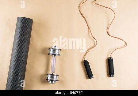Yoga mat with dumbbell and leather jumping rope Stock Photo - Alamy