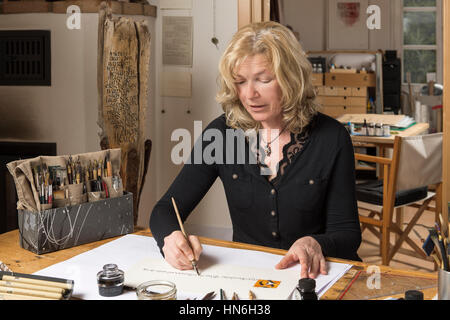 Woman writes with pen in handmade carrot shaped casing at beige table ...