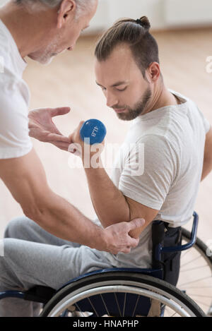 Concentrated disabled man in wheelchair working on spinal injury ...
