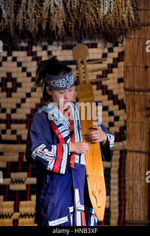 Ainu woman playing a traditional instrument in Ainu village museum ...