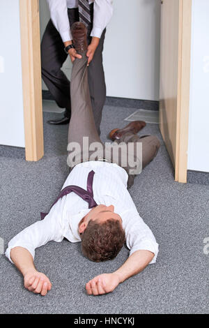 Businessmen pulling colleague's leg at office Stock Photo - Alamy