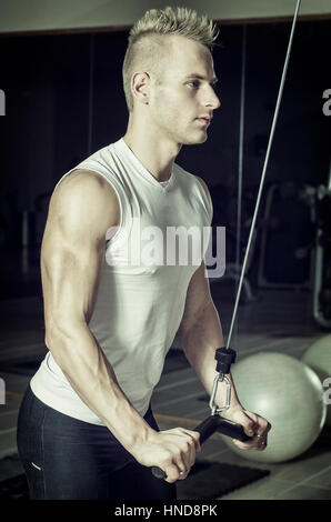 Man pulling cables. Handsome athlete male lifting up and push up on ...