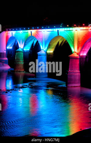Rainbow bridge illuminated by glowing colored lights at night with ...