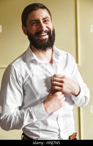 Young and fashionable man buttoning a cuff and posing outdoor on a ...