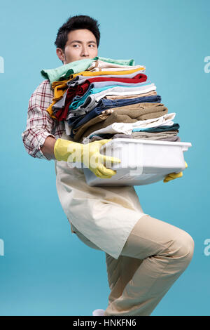 Young man carrying heavy laundry basket by washing machine at home ...