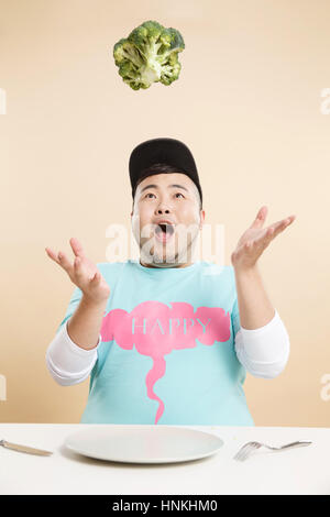 Young overweight man with fork and knife near unhealthy food at home ...