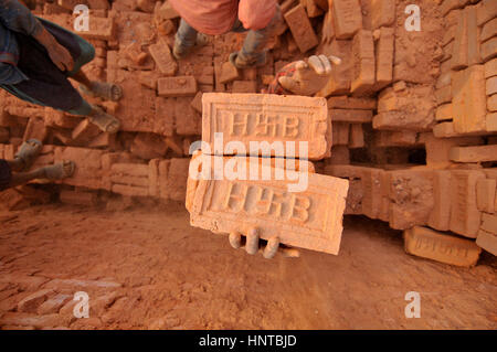 A Migrant Indian labourer stacks bricks to carry at a brick factory in ...