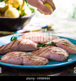 Woman squeezing juice from lemon on trout on restaurant terrace Stock ...