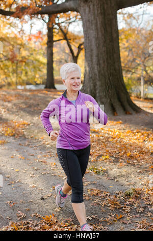 Senior woman running jogging exercising along a path outdoors in a ...