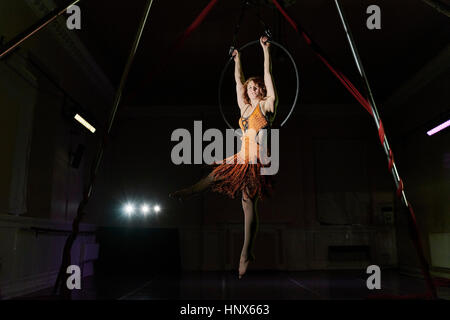 Young female acrobat poised hanging from hoop Stock Photo - Alamy