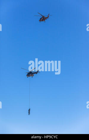 Soldiers attached to rope flying airlift below helicopter military ...