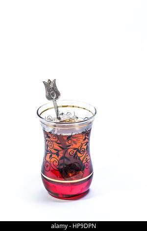 Glass with tea and teaspoon inside on wooden table and saucer with ...