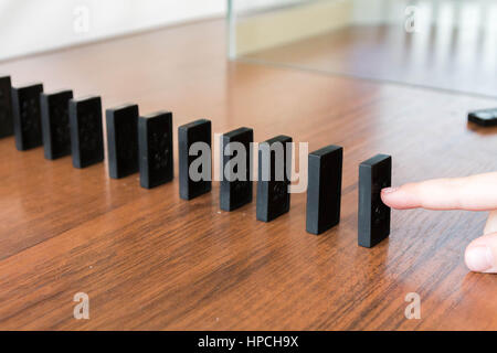 Hand pushing dominoes. Topple track of dominoes Stock Photo - Alamy