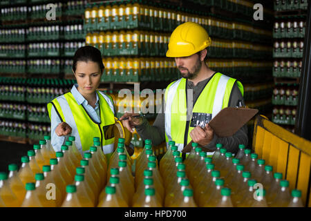 Two factory workers monitoring cold drink bottles on production line at ...