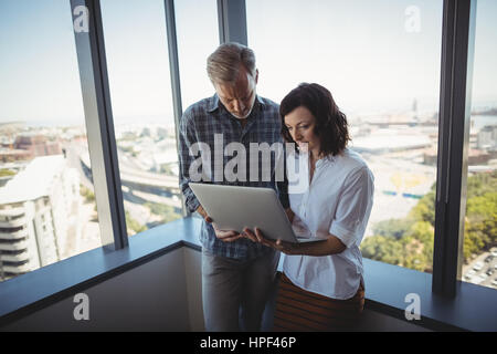 Executives using laptop near the window in office Stock Photo - Alamy