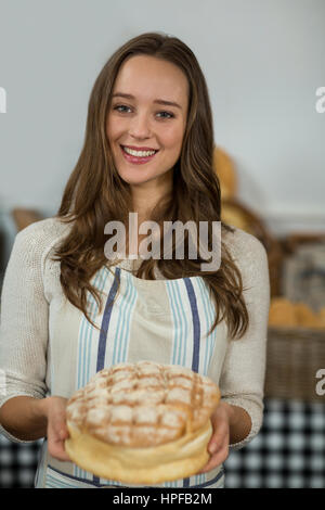 Smiling young bakery seller offering freshly baked pastries Stock Photo ...
