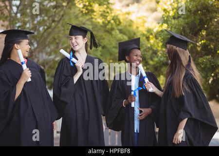 Smiling graduate school kids standing with degree scroll in campus at ...