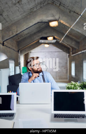 Thoughtful young bearded man with laptop at table in kitchen Stock ...