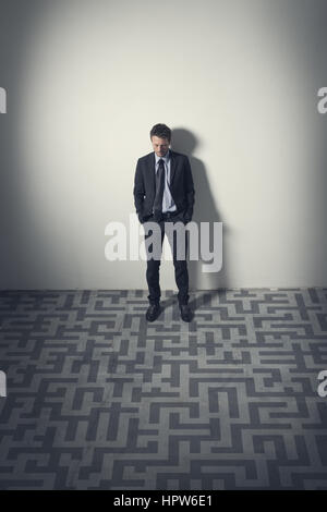 Businessman in doubt looking to a maze and searching the way out Stock ...