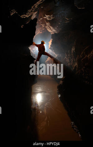 Man exploring cave with light beam Stock Photo - Alamy
