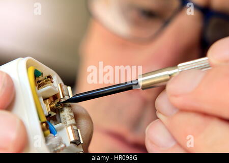 Man wiring English 3 pin 13 amp plug - inserting live wire, England, UK ...