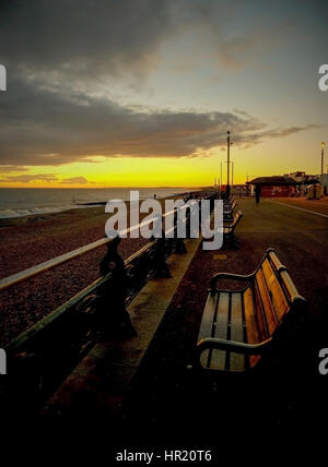 A line of benches on Brighton seafront on a wet day with the pier in ...