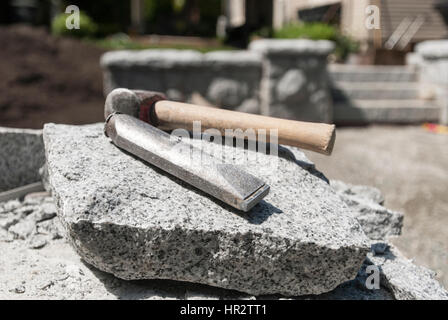 A stone mason uses a hammer and chisel to break a large stone Stock ...