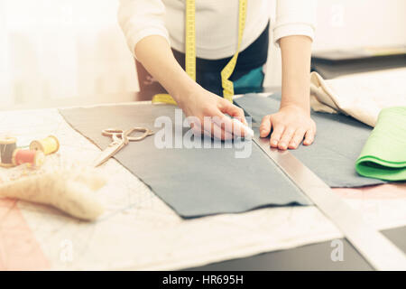 Woman tailor working on a clothing sewing stitching measuring fabric ...