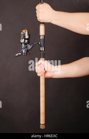 Man's hand holding a fishing rod on a black background Stock Photo - Alamy