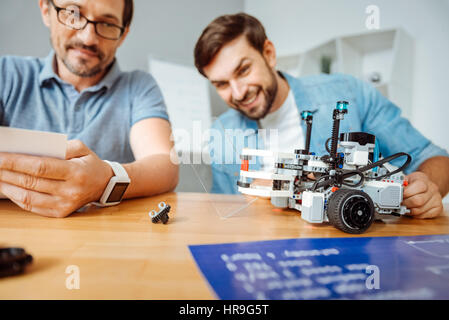 Positive engineers testing robot Stock Photo - Alamy