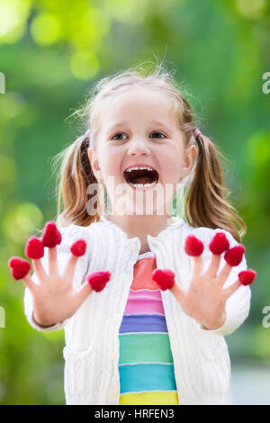 Child picking raspberry. Kids pick fresh fruit on organic raspberries ...