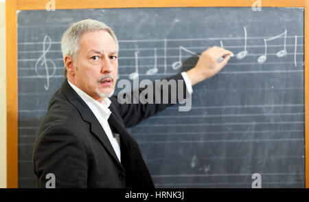 Teacher writing music notes with chalk on blackboard in classroom Stock ...